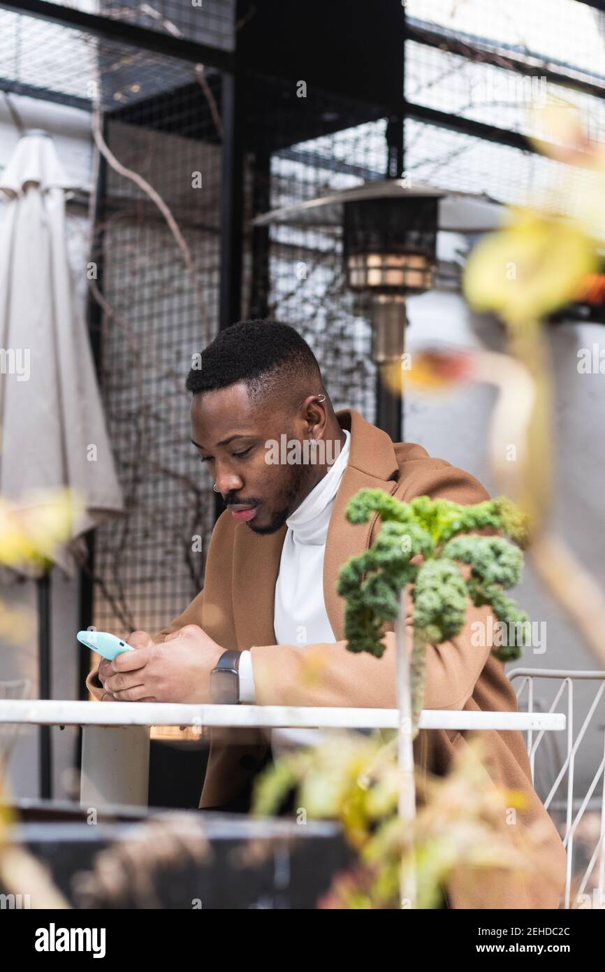 Young African American male with wristwatch browsing on mobile phone ...