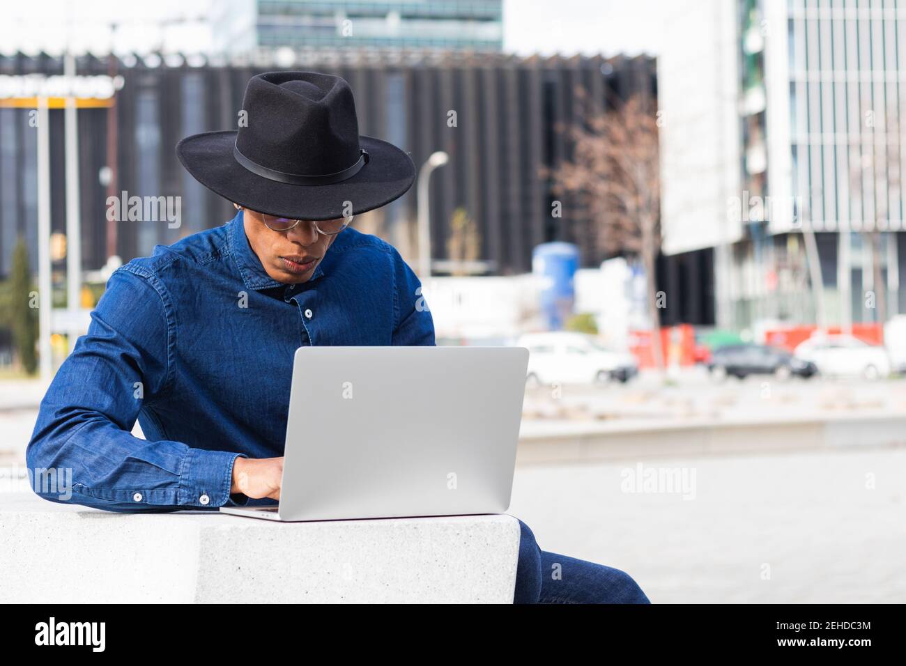 Stylish unrecognizable concentrated ethnic male remote employee in hat ...