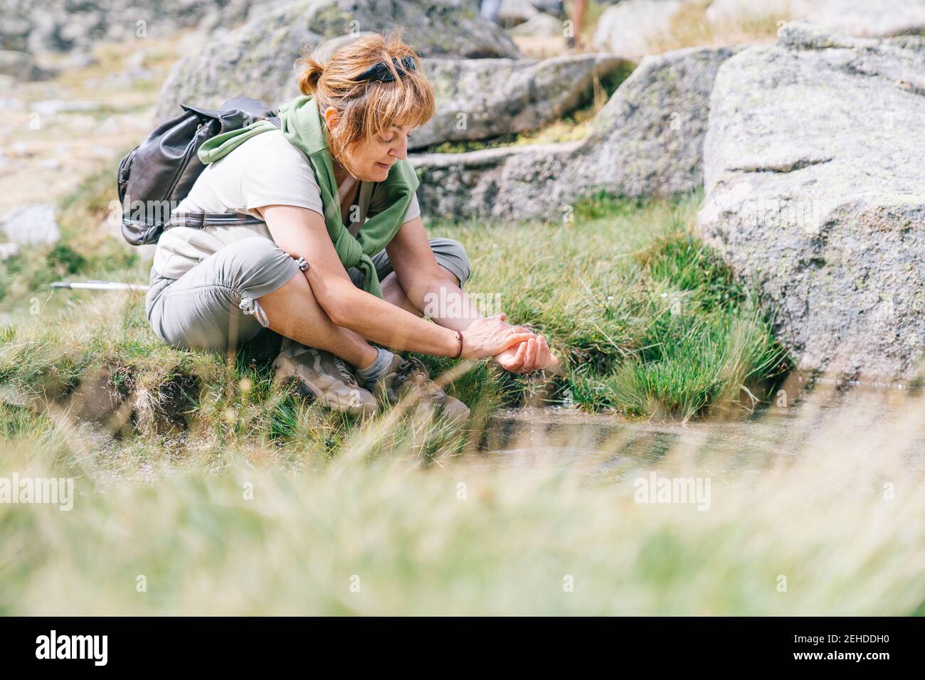 Full body content adult female backpacker in casual wear washing hands ...