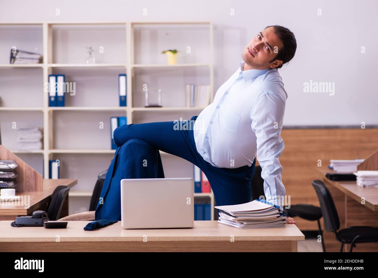 Young employee doing physical exercises at workplace Stock Photo - Alamy