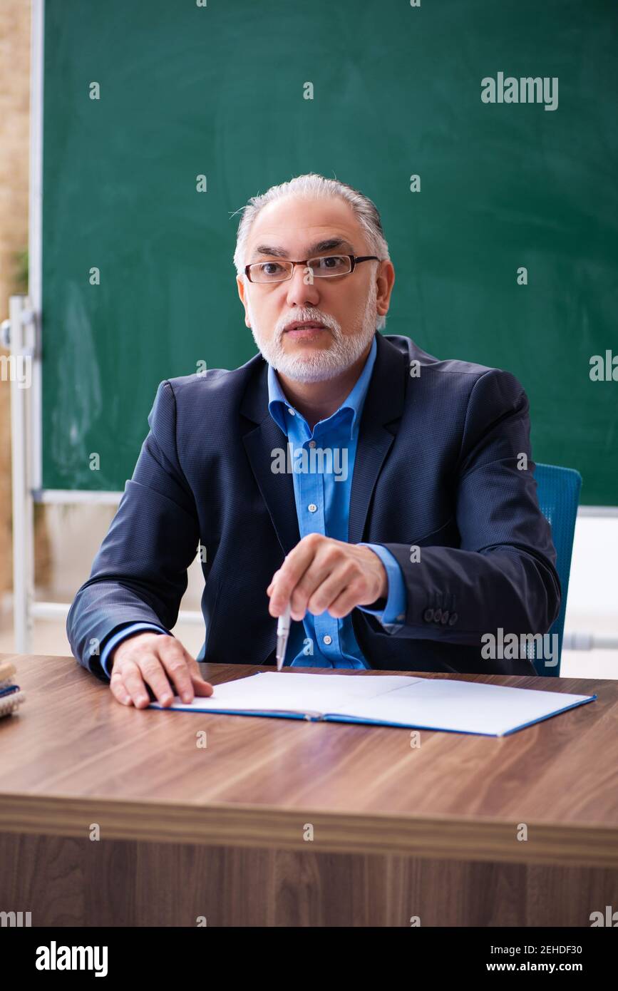 Aged male math teacher in the classroom Stock Photo - Alamy