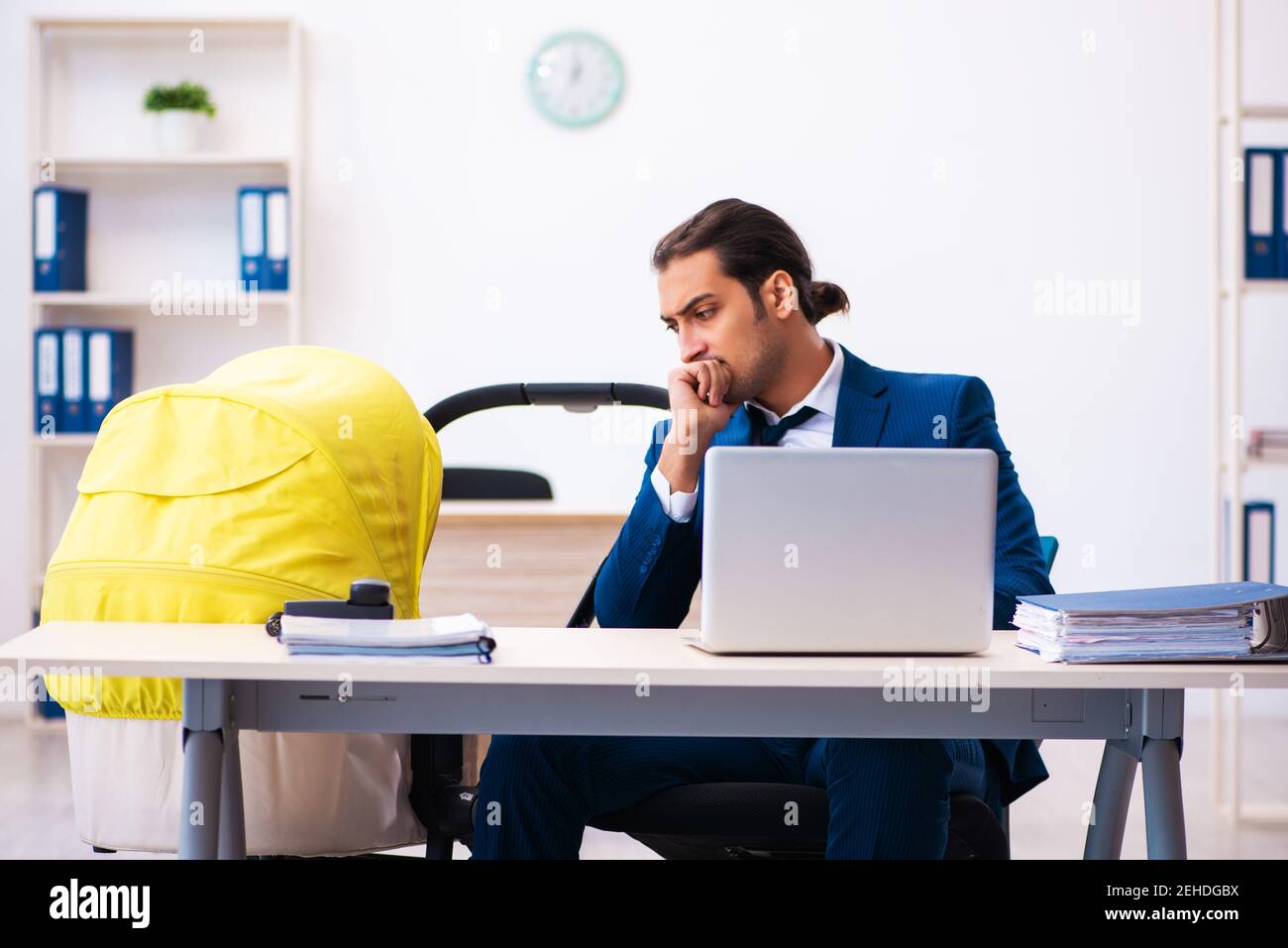 Young employee looking after kid at workplace Stock Photo - Alamy