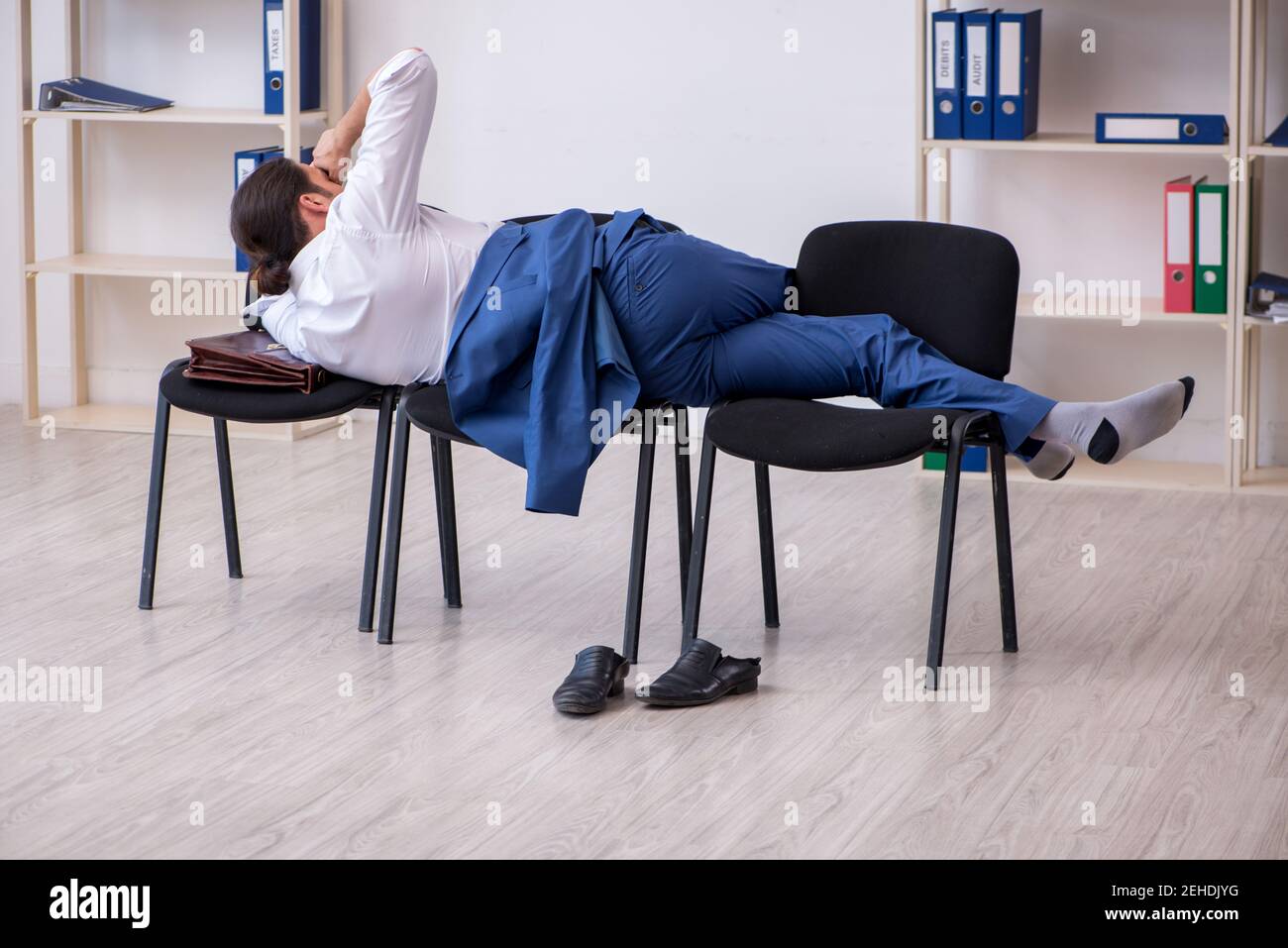 Young employee sleeping in the office on chairs Stock Photo - Alamy
