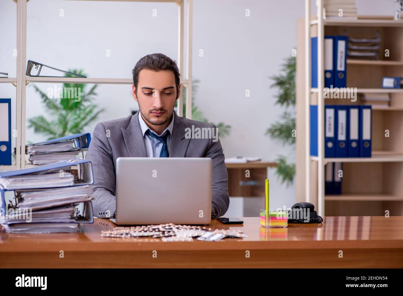 Male sick employee suffering at workplace Stock Photo - Alamy