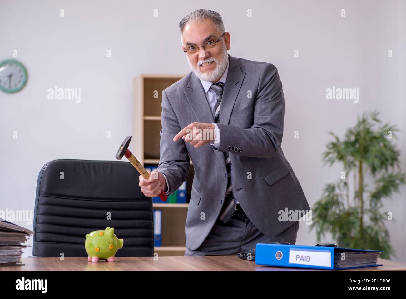 Old employee holding hammer in budget planning concept Stock Photo - Alamy