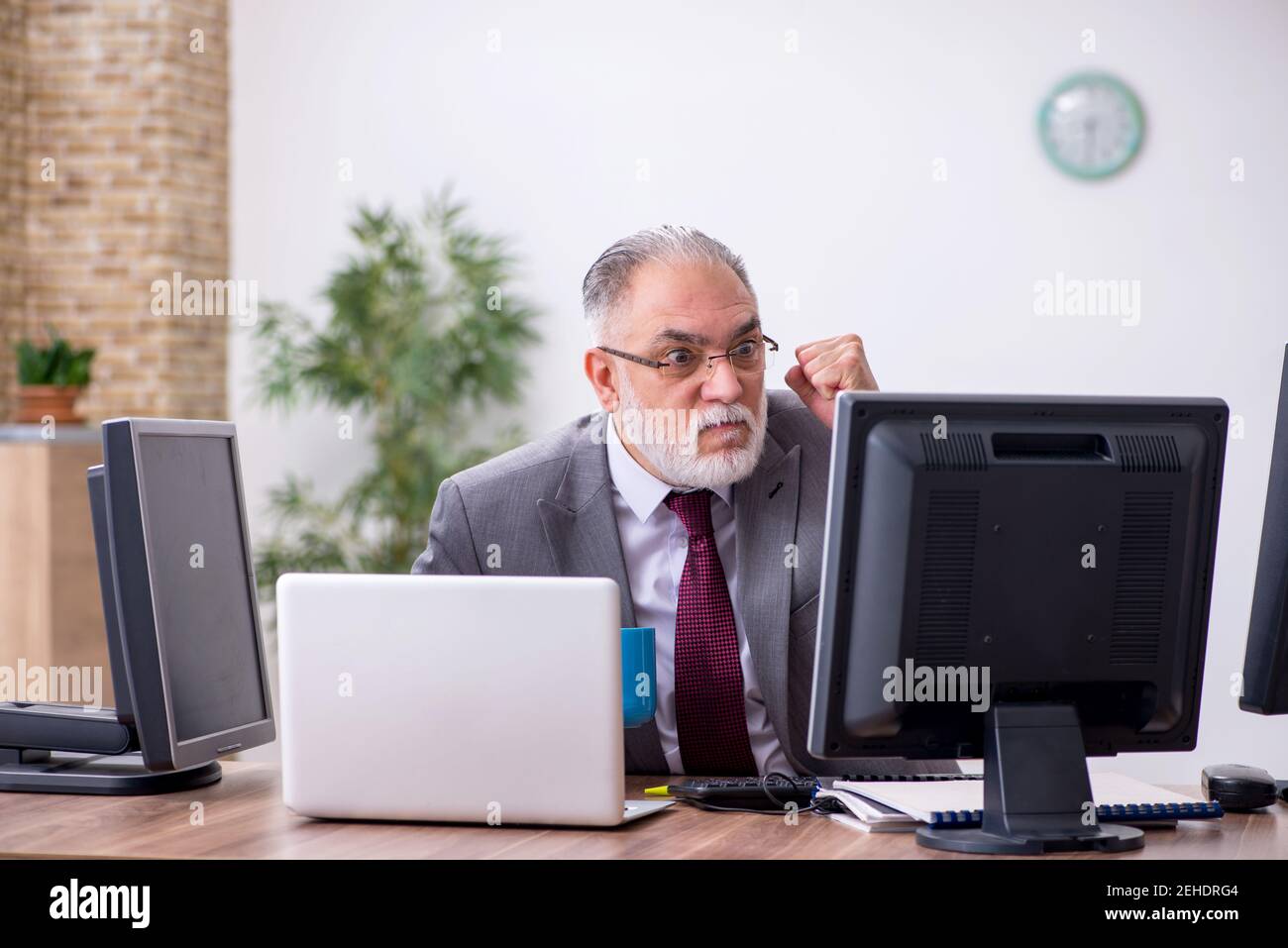 Old boss sitting at desktop in the office Stock Photo - Alamy