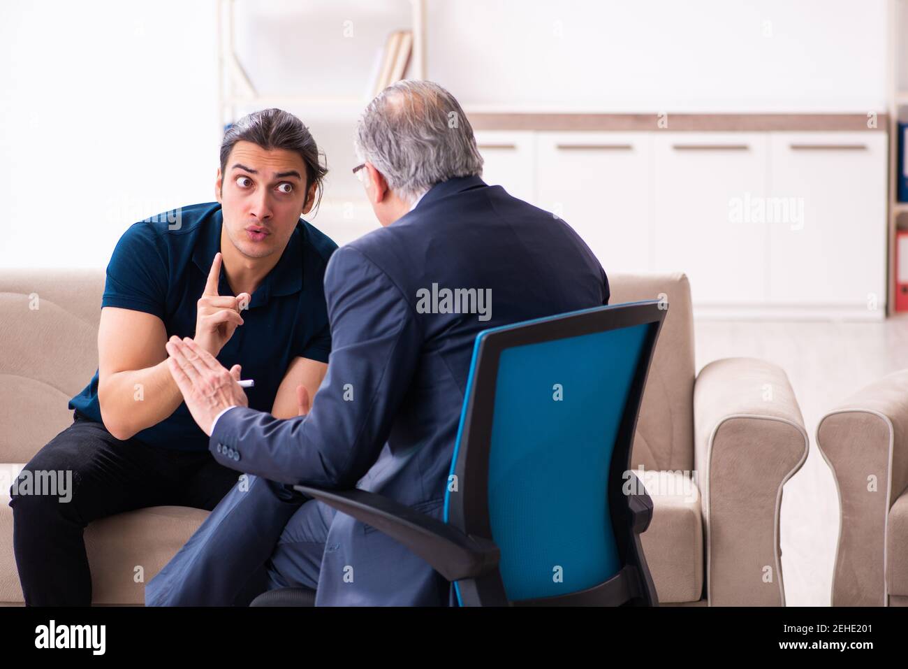 Young man visiting old psychologist Stock Photo - Alamy