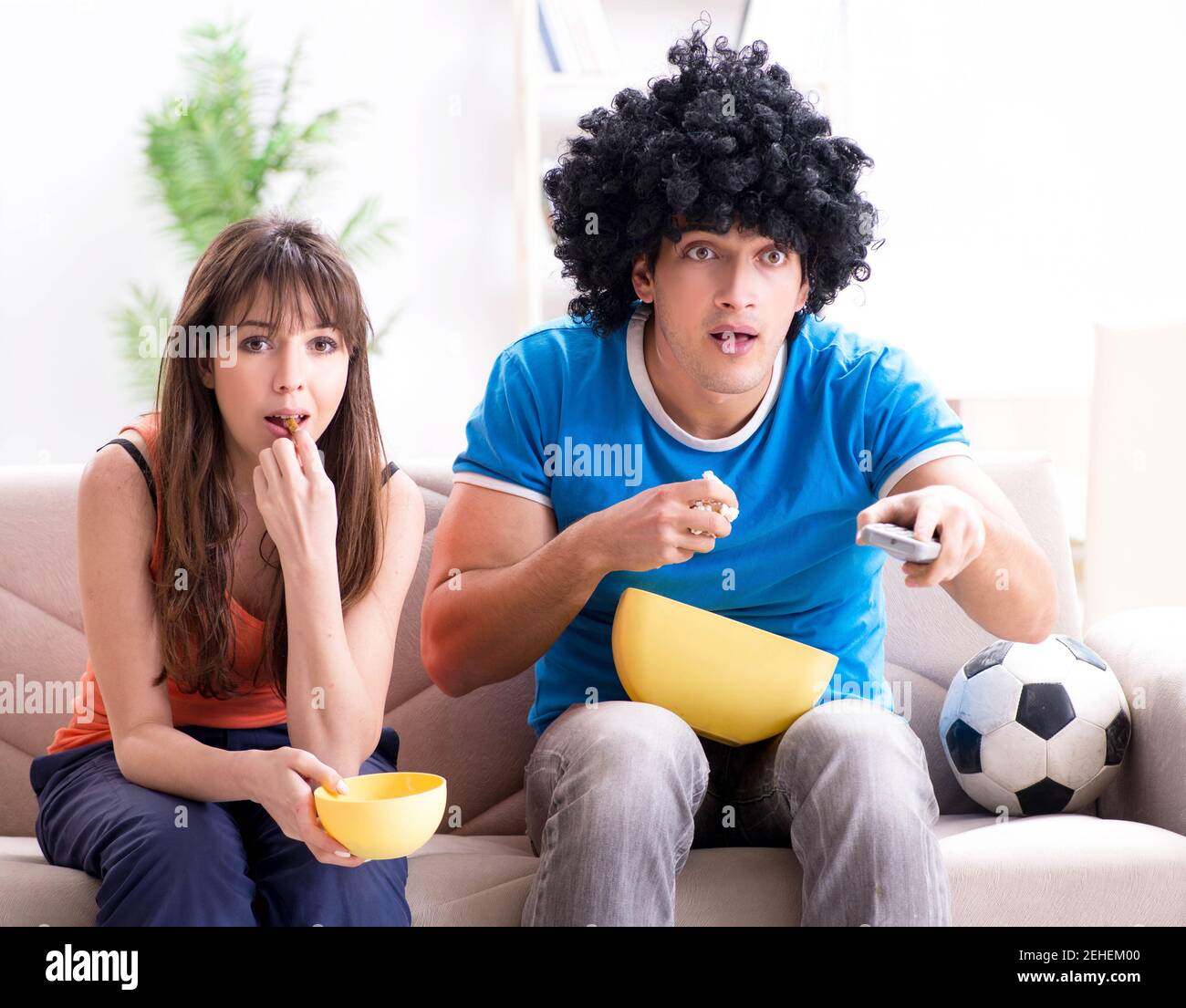 The young man watching football with his wife at home Stock Photo - Alamy
