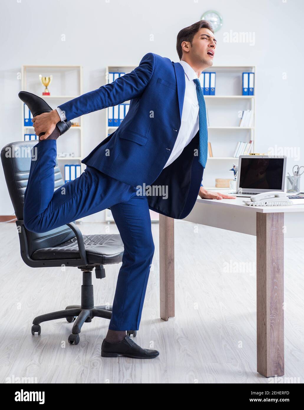 The young businessman doing sports stretching at workplace Stock Photo ...