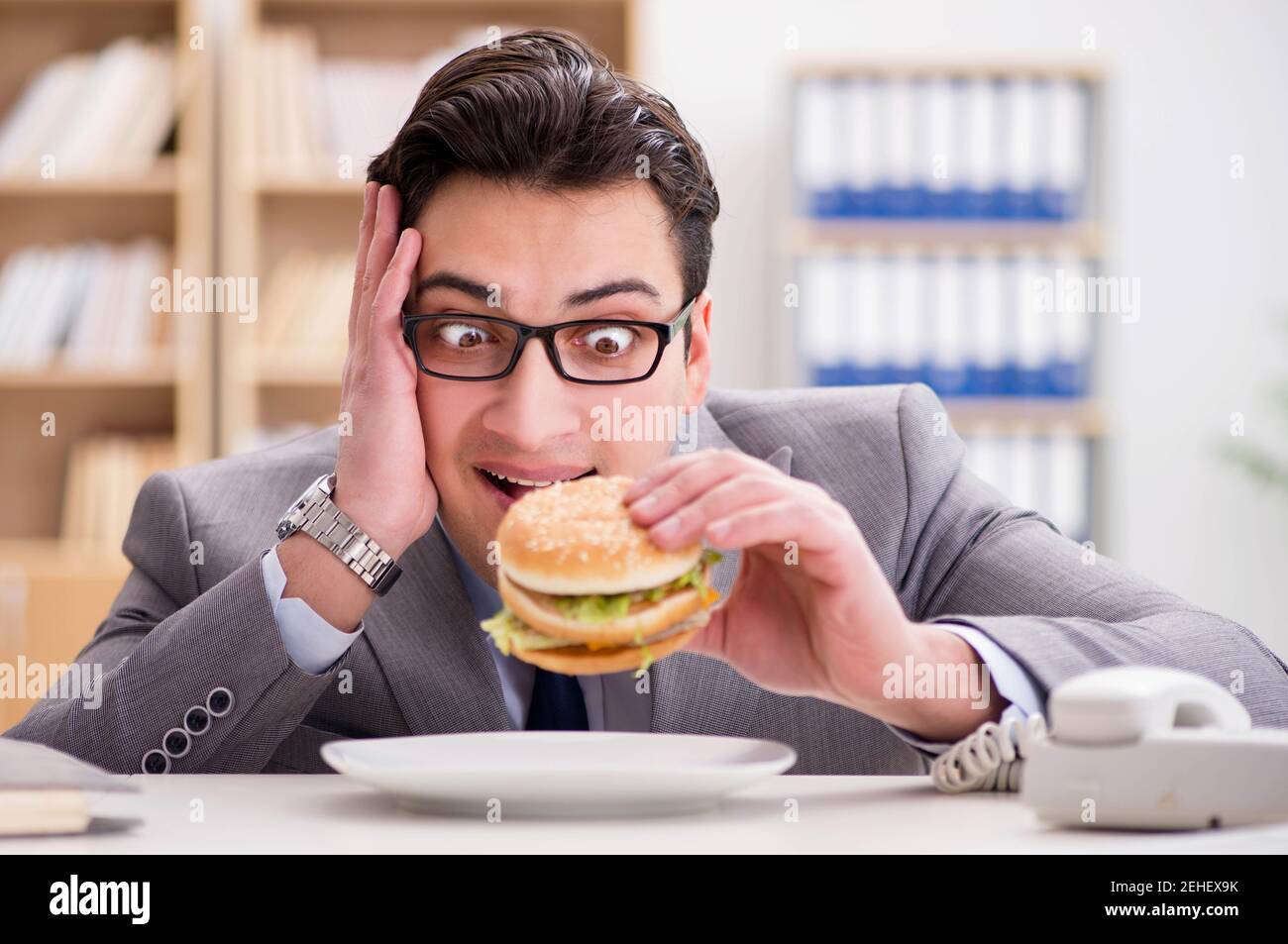 The hungry funny businessman eating junk food sandwich Stock Photo - Alamy
