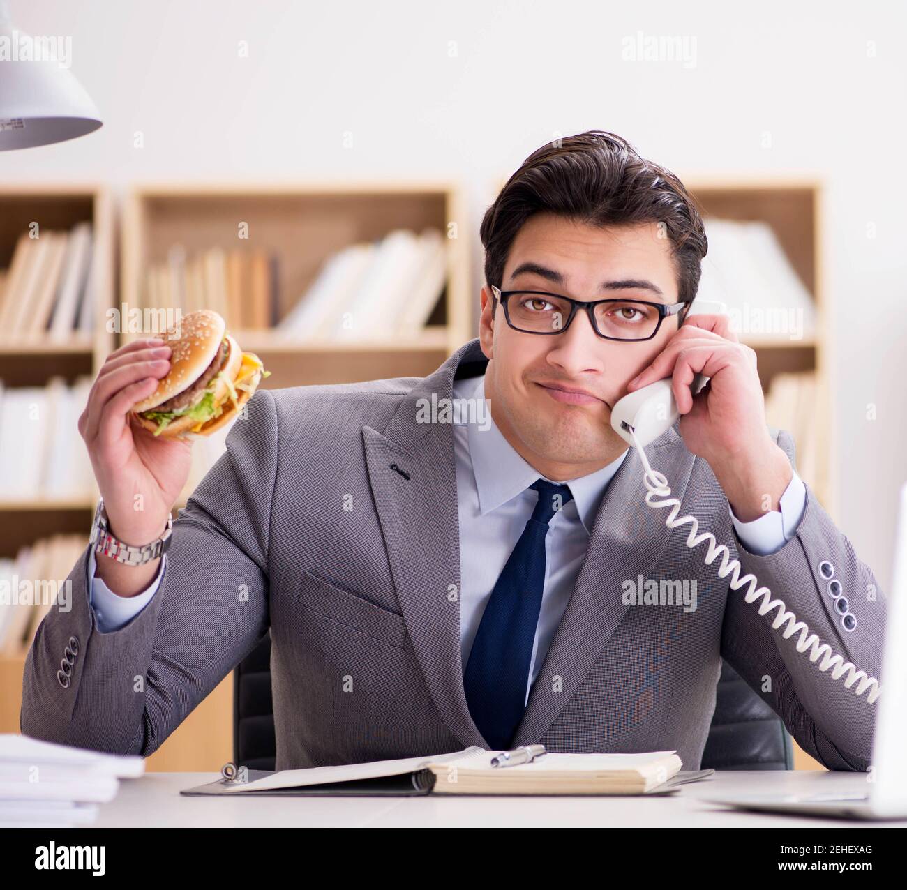 The hungry funny businessman eating junk food sandwich Stock Photo - Alamy