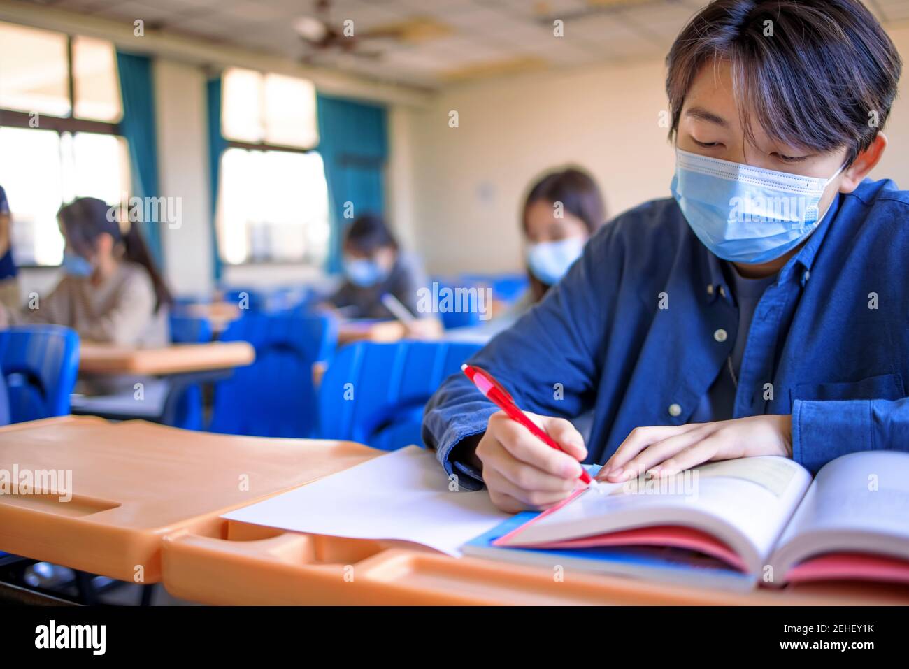 Group of students wearing protection masks and studying in classroom ...