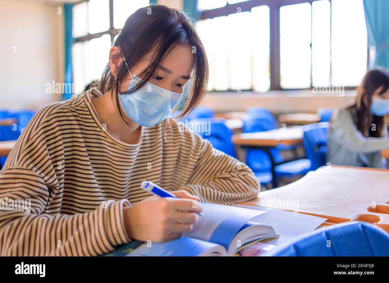 Teenager students wearing protection masks and studying in classroom ...
