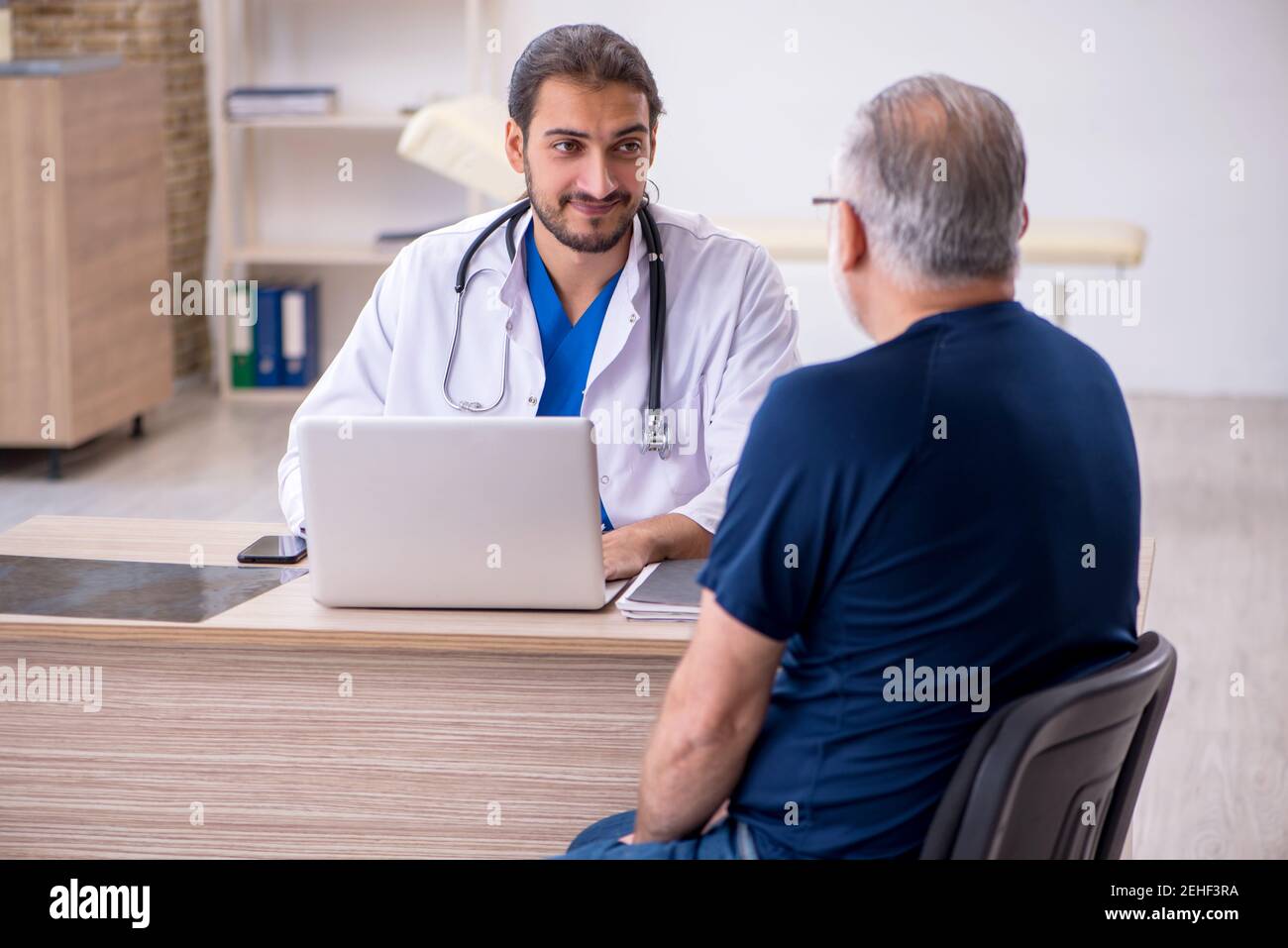 Old male patient visiting young doctor Stock Photo - Alamy
