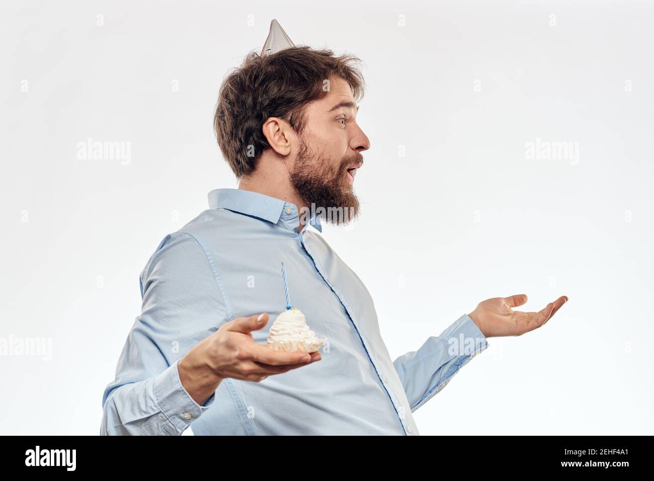 a man with a beard holds a cake in his hand on a light background ...