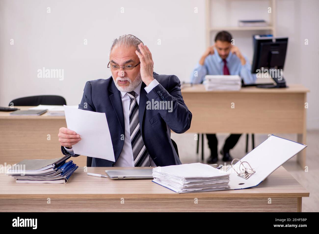 Old boss and young employee working in the office Stock Photo - Alamy