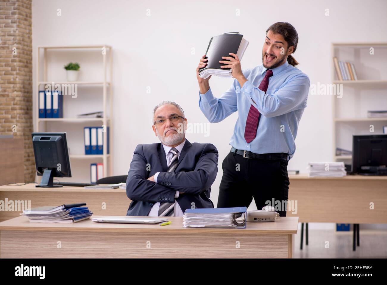 Old boss and young employee working in the office Stock Photo - Alamy