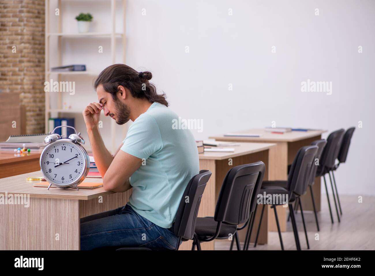 Young student in the classroom in time management concept Stock Photo ...