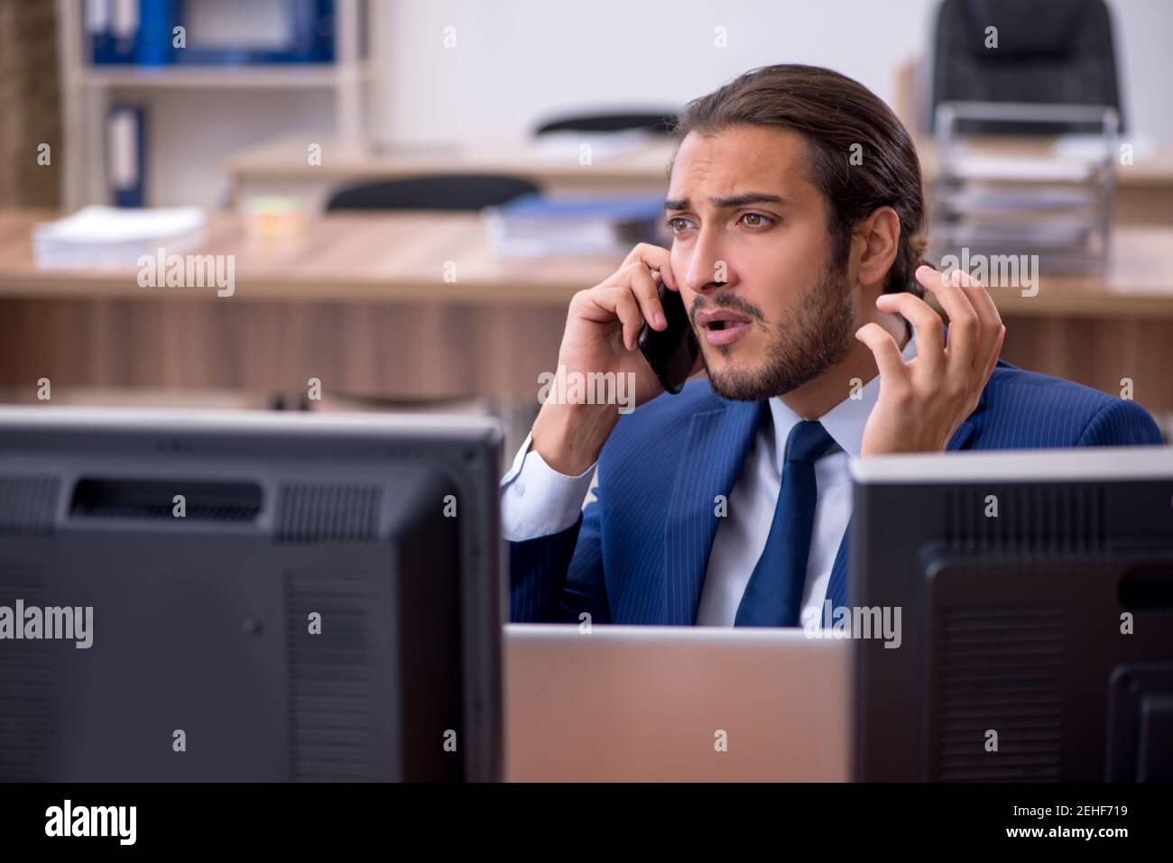 Young employee in multitasking concept Stock Photo - Alamy