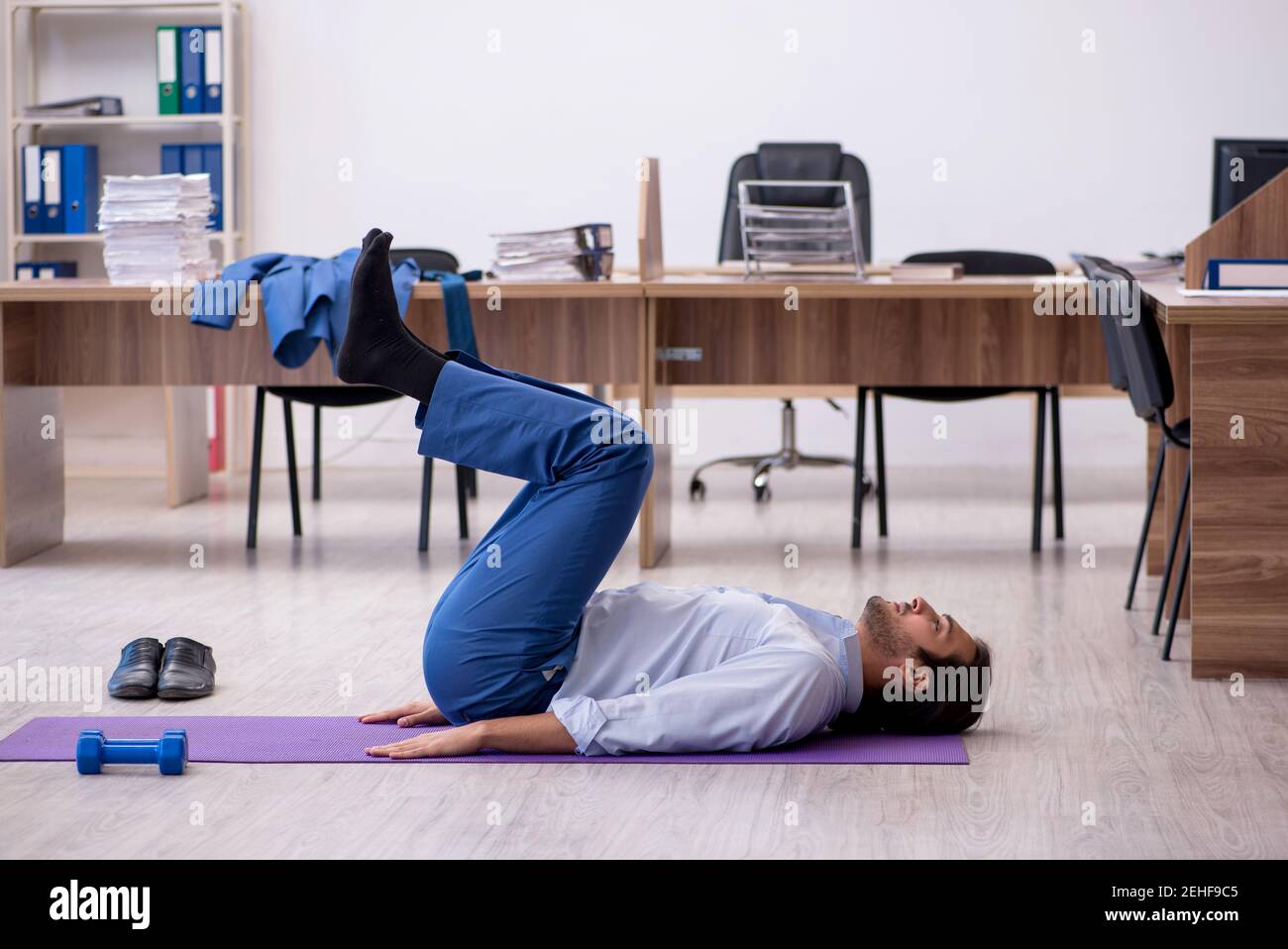 Young employee doing sport exercises during break Stock Photo - Alamy