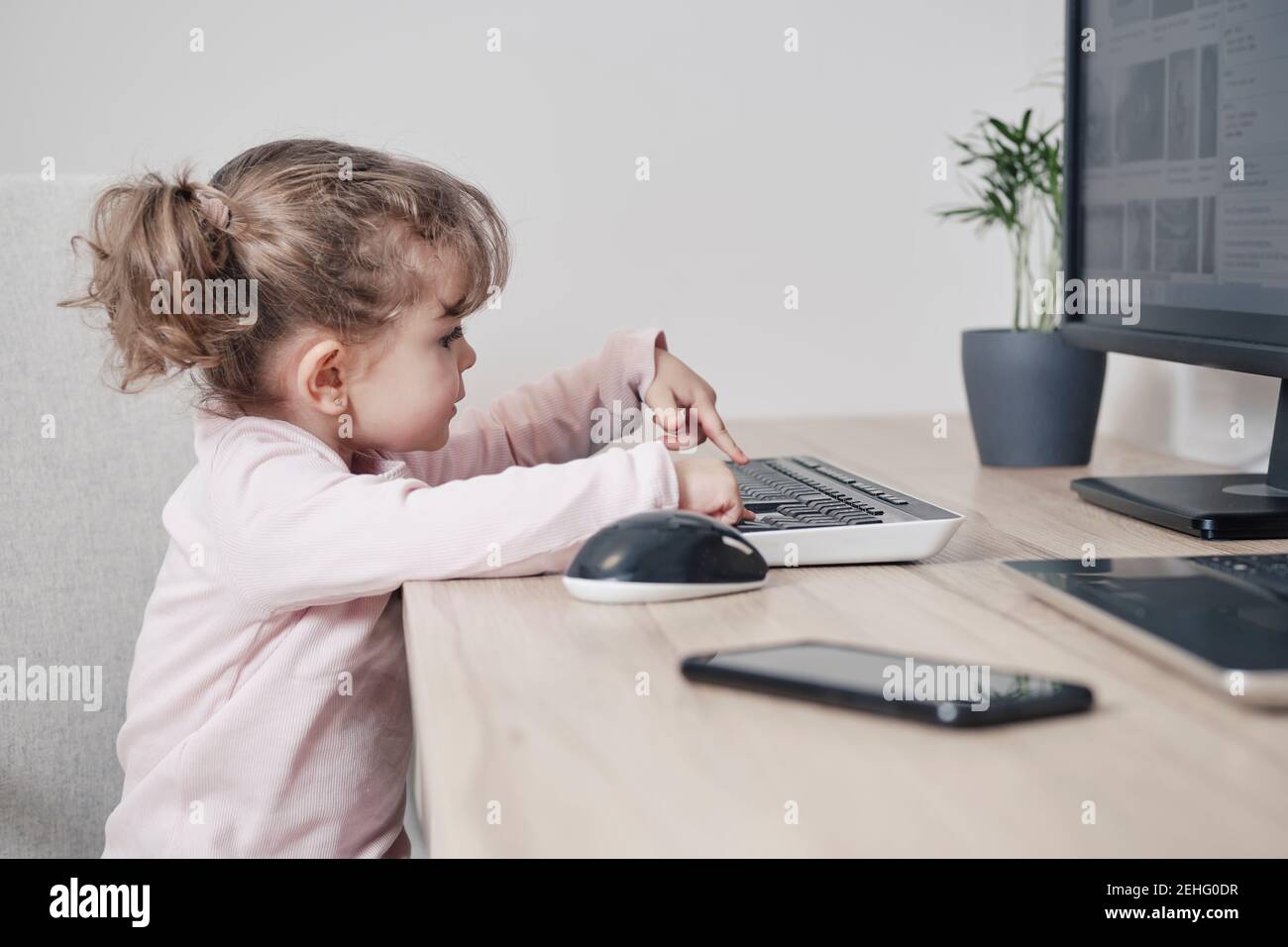 A 2 year old girl is using a computer keyboard while sitting in an ...