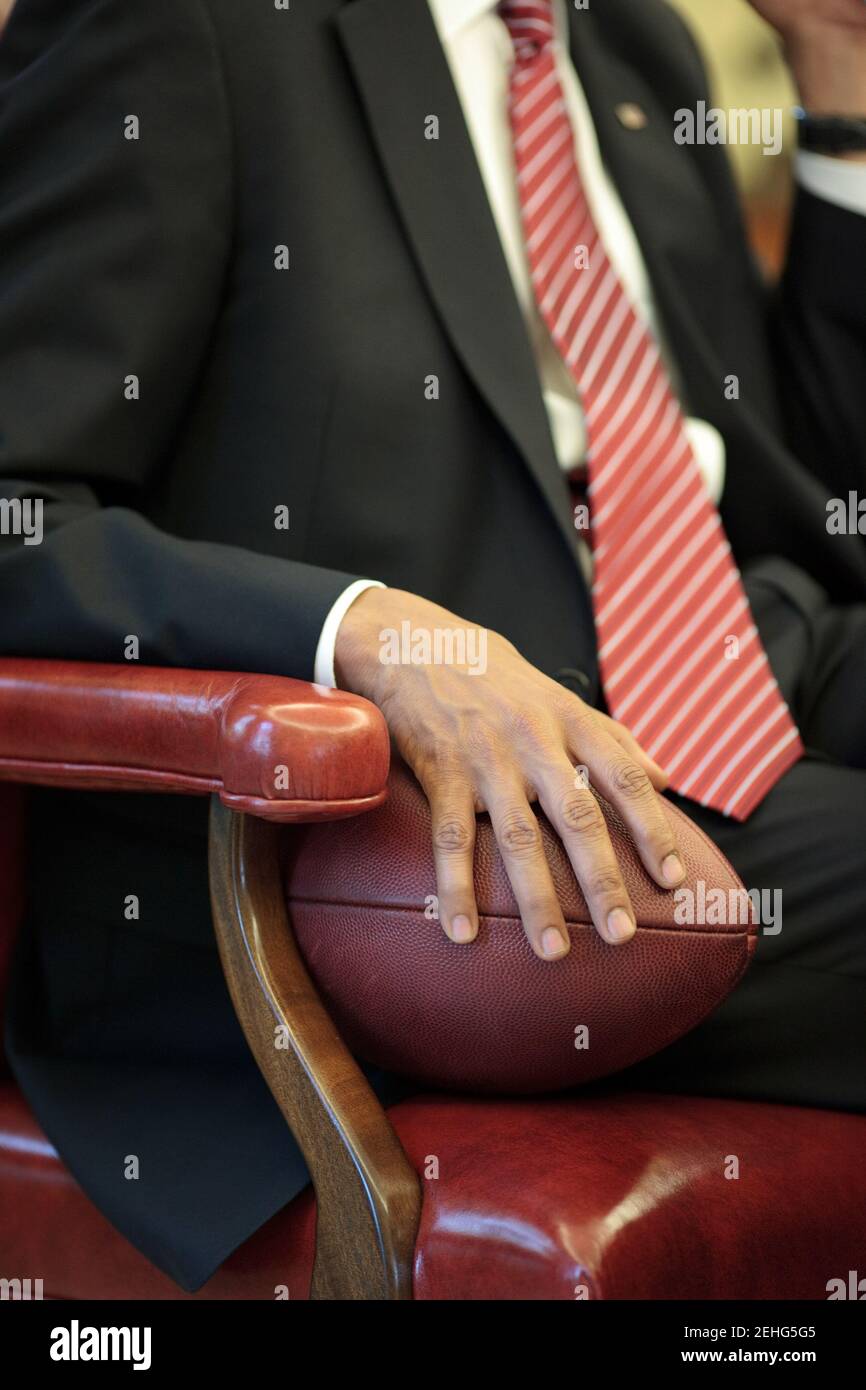 President Barack Obama holds a football while taking a phone call in ...
