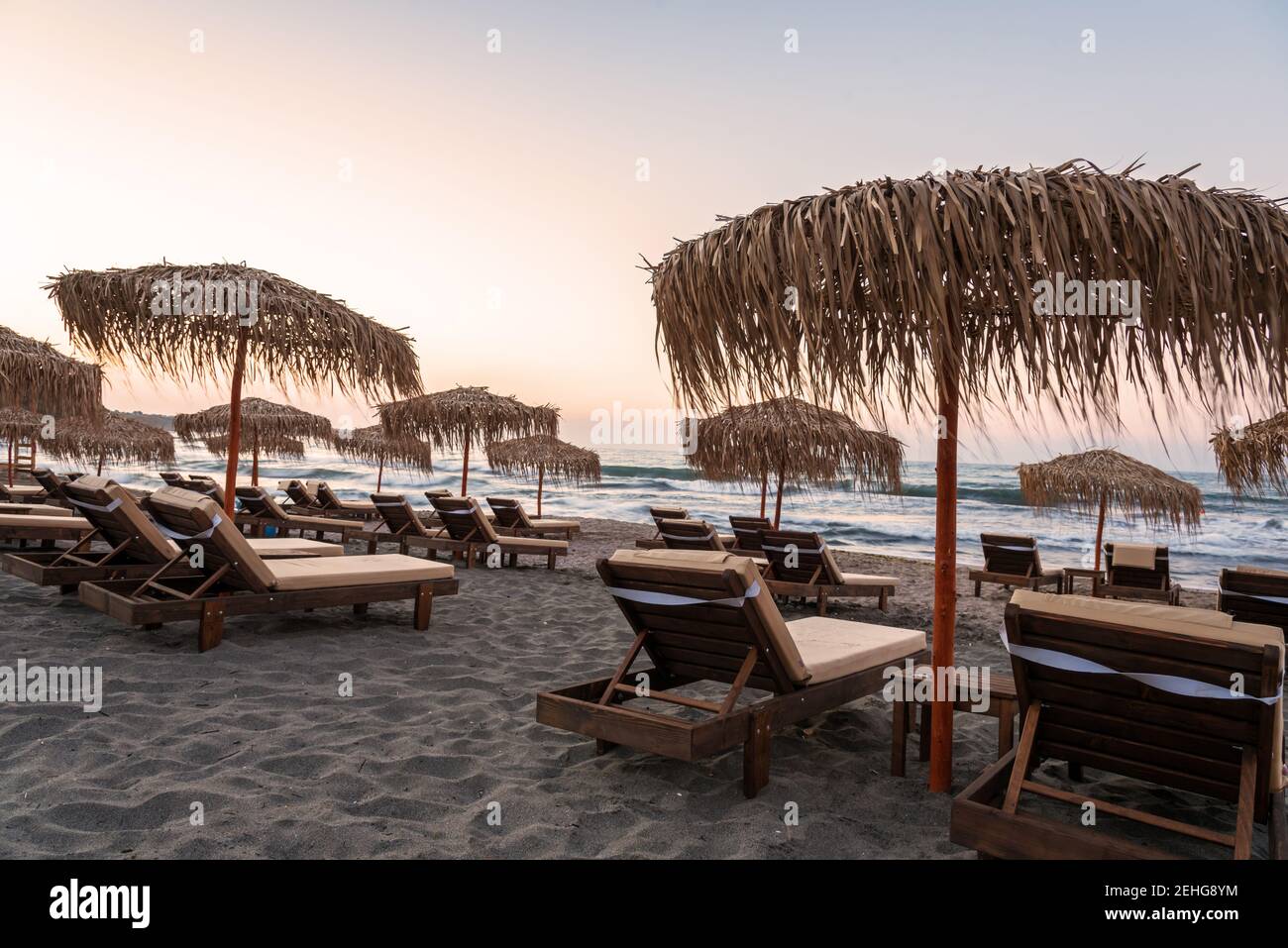 Parasol and sun bed loungers on empty tropical beach at sunset with ...