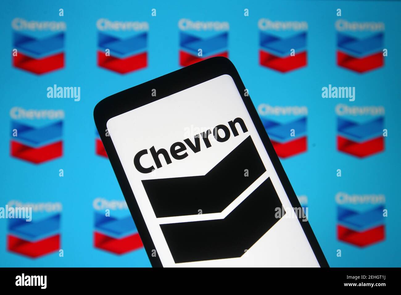 In this photo illustration a Chevron logo is seen on a smartphone and a ...