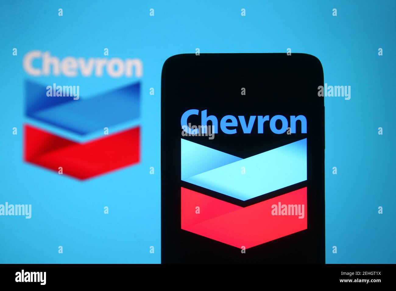 In this photo illustration a Chevron logo is seen on a smartphone and a ...