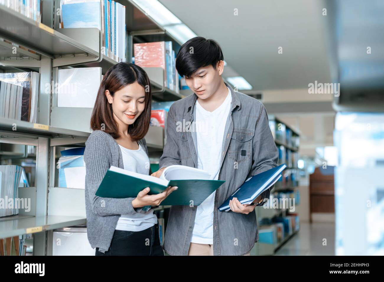 Student college opening and reading a book at library Stock Photo - Alamy