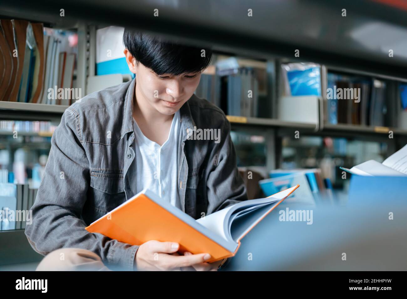 Student college opening and reading a book at library Stock Photo - Alamy
