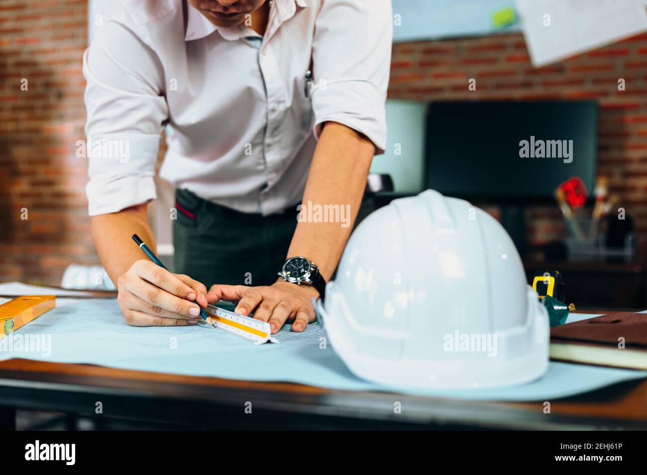 engineers holding a pen pointing to a building and drawing outlay ...