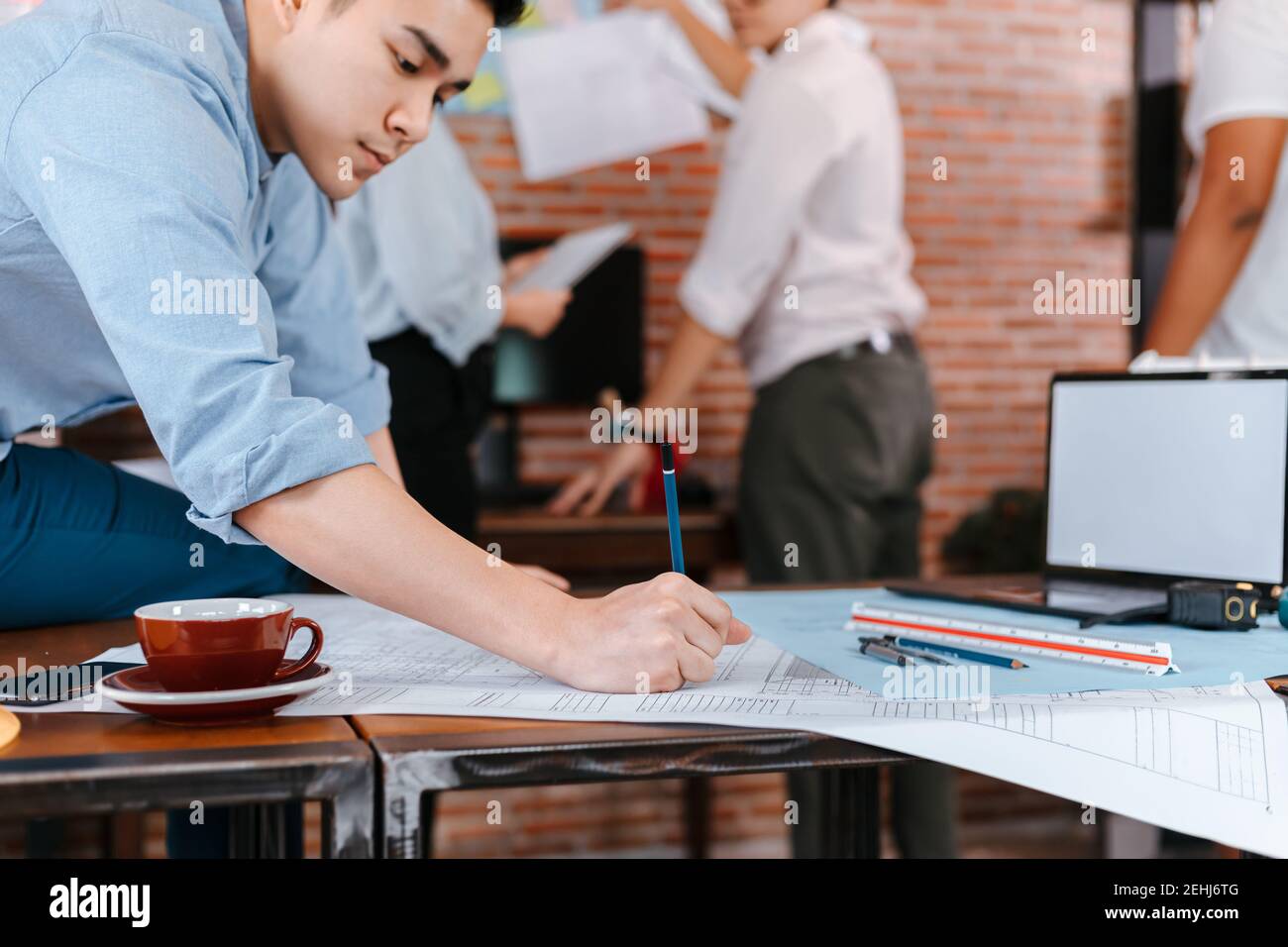engineers holding a pen pointing to a building and drawing outlay ...