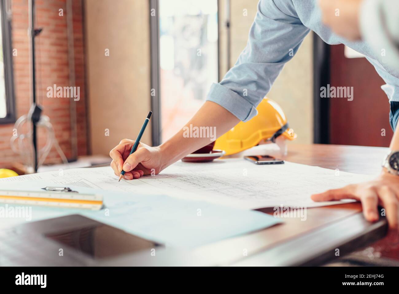 engineers holding a pen pointing to a building and drawing outlay ...