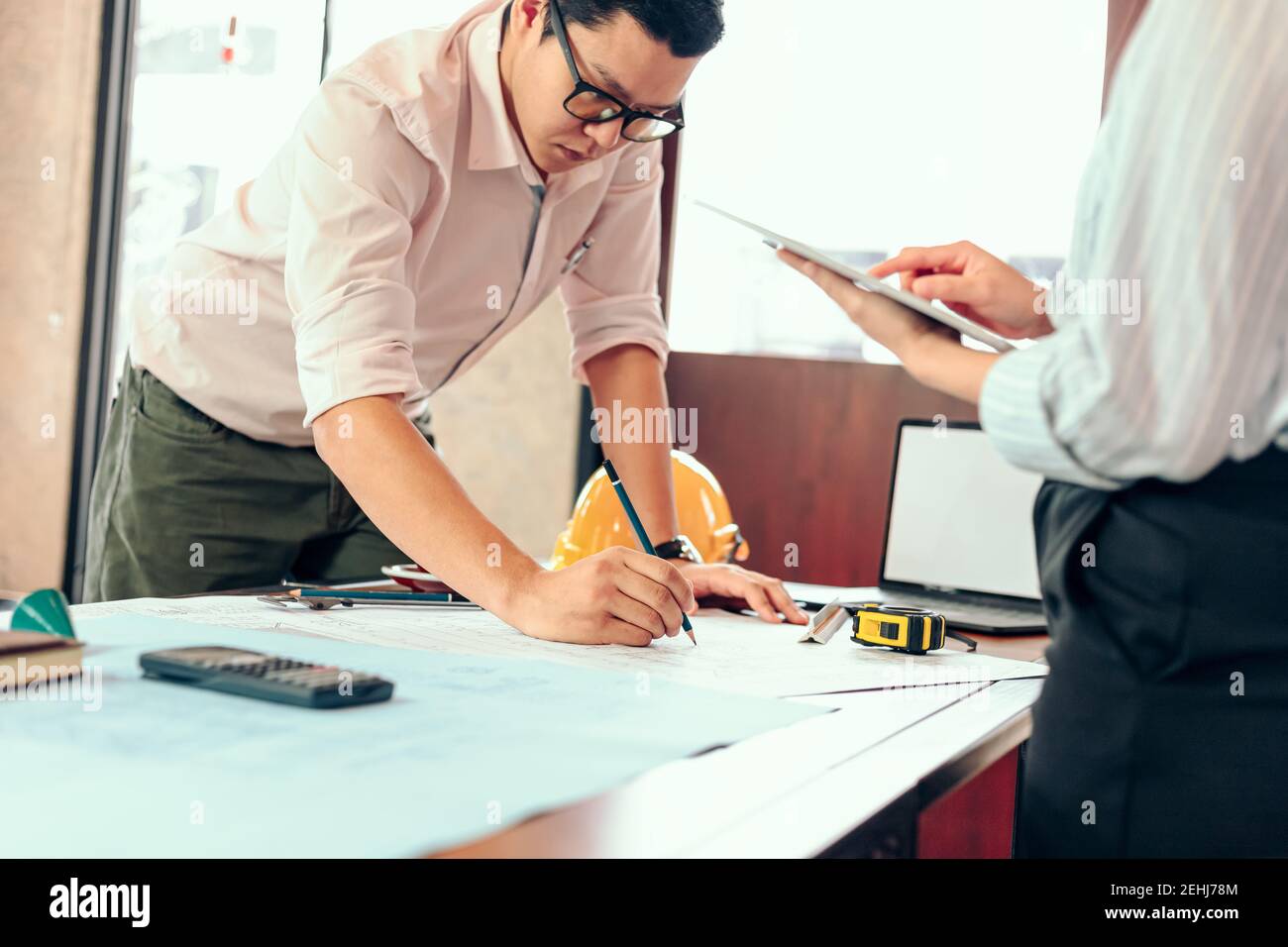 engineers holding a pen pointing to a building and drawing outlay ...