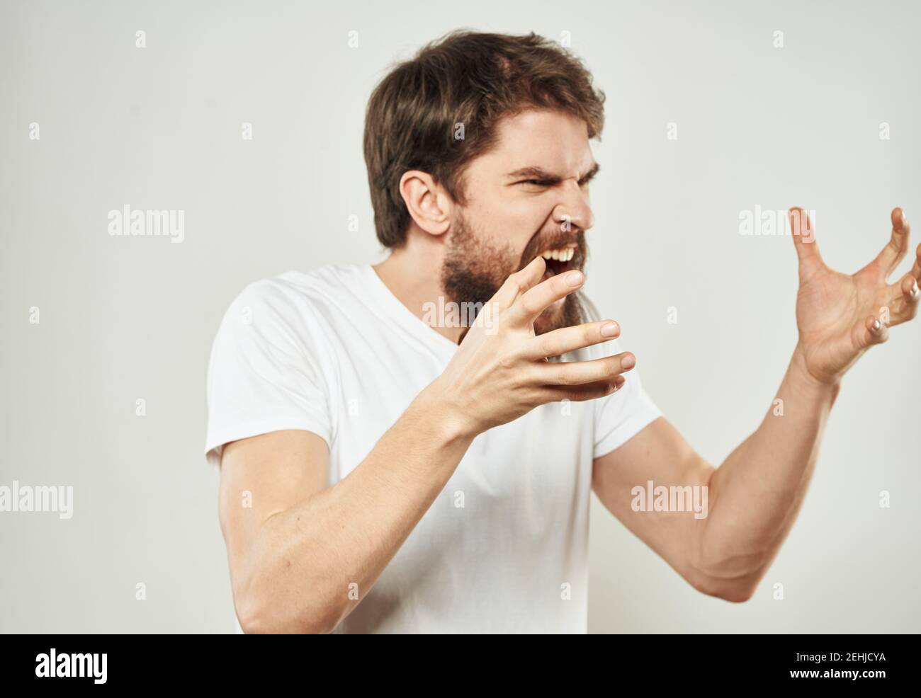 Aggressive man gestures with his hands on a light background stress ...