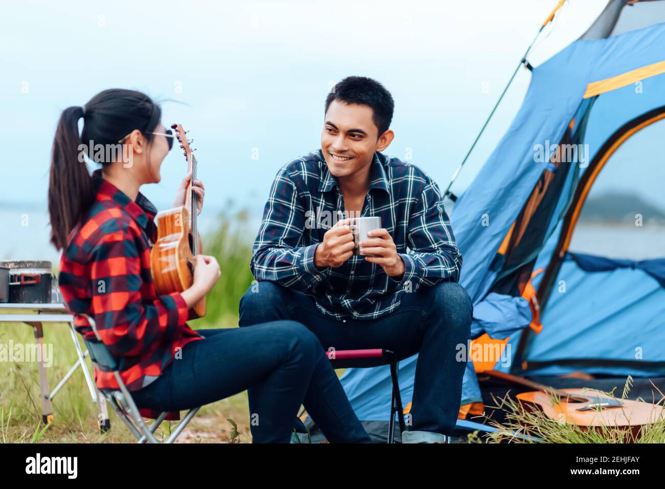 Group of friends camping and they are sitting playing guitar. Camp and ...