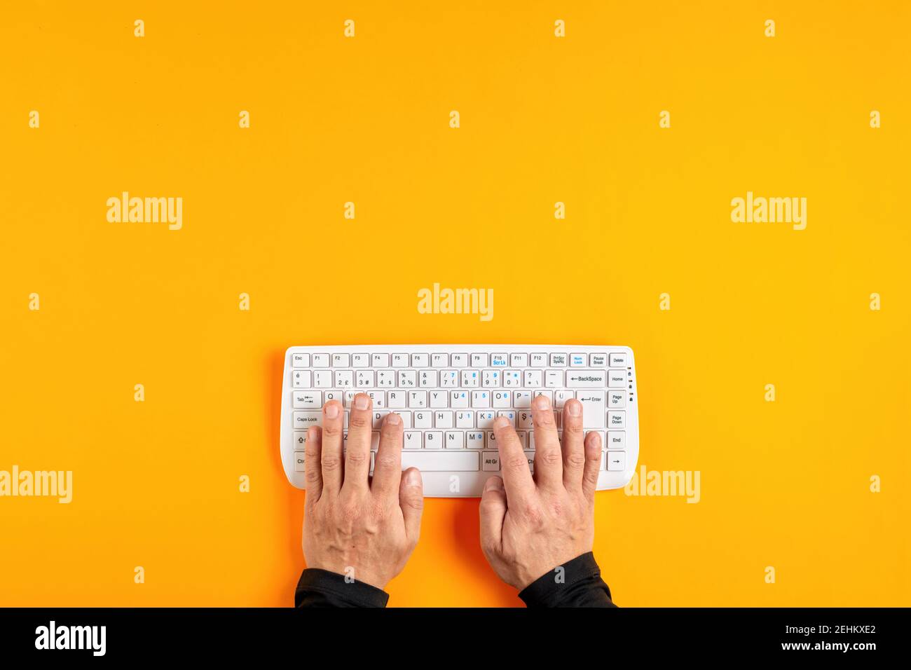 Male hands using a white computer keyboard on yellow background Stock ...