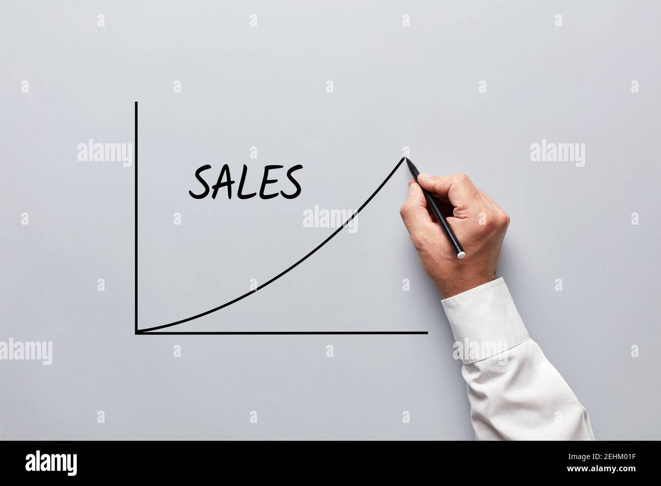 Male hand drawing a graph of sales on gray background. Increasing sales ...