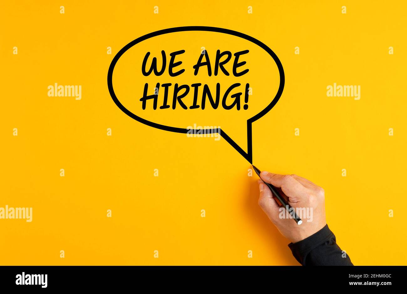 Male hand drawing a speech balloon with the message of we are hiring on ...