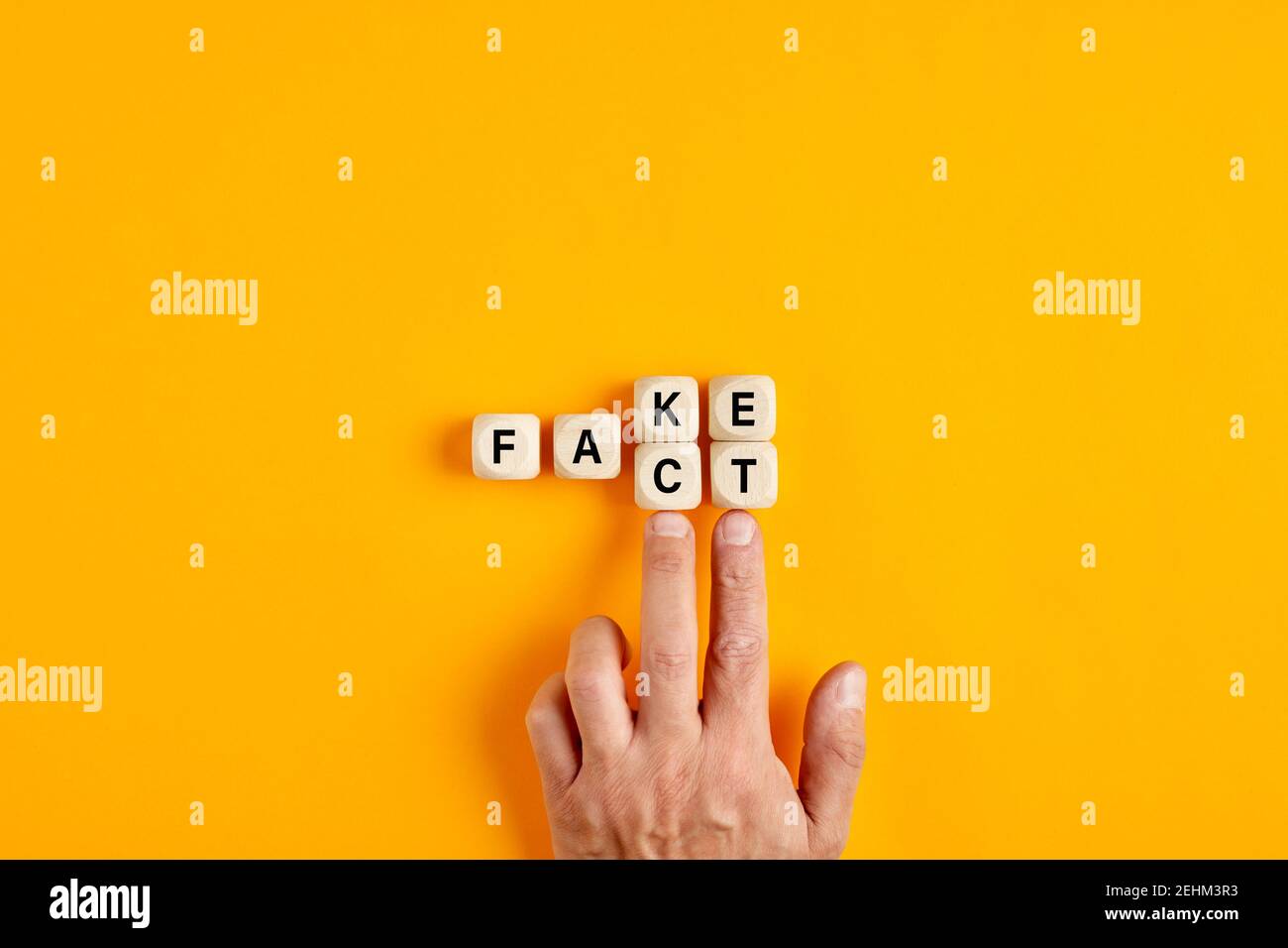 Male hand pushing the wooden cubes and transforming the word fake to ...