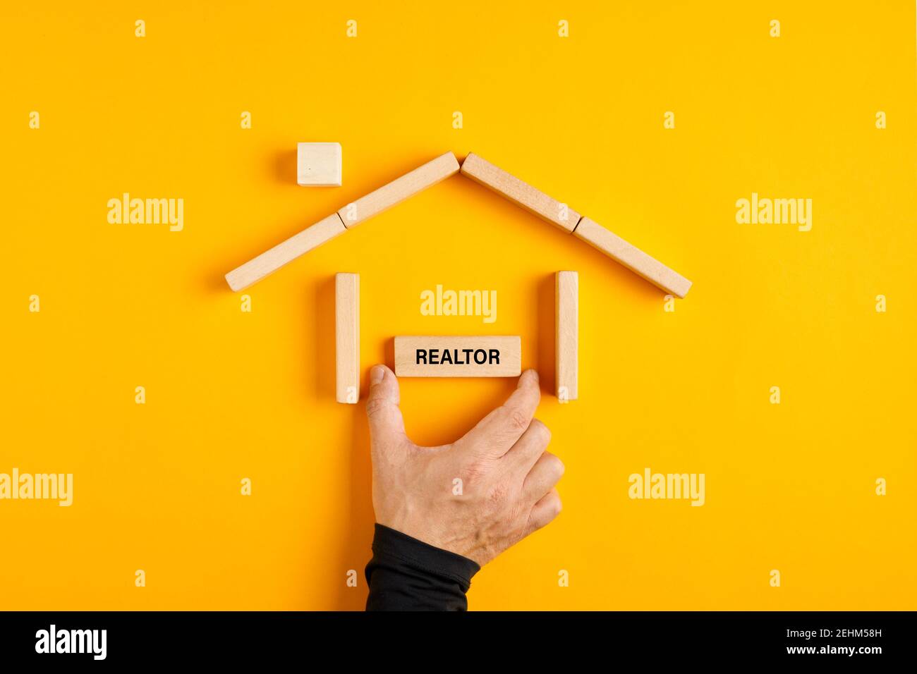 Male hand placing realtor sign in a house made of wooden blocks on ...