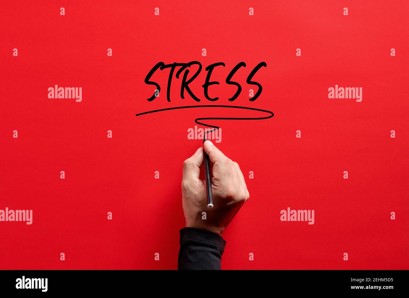 Male hand writing the word stress on red background. Overhead view ...