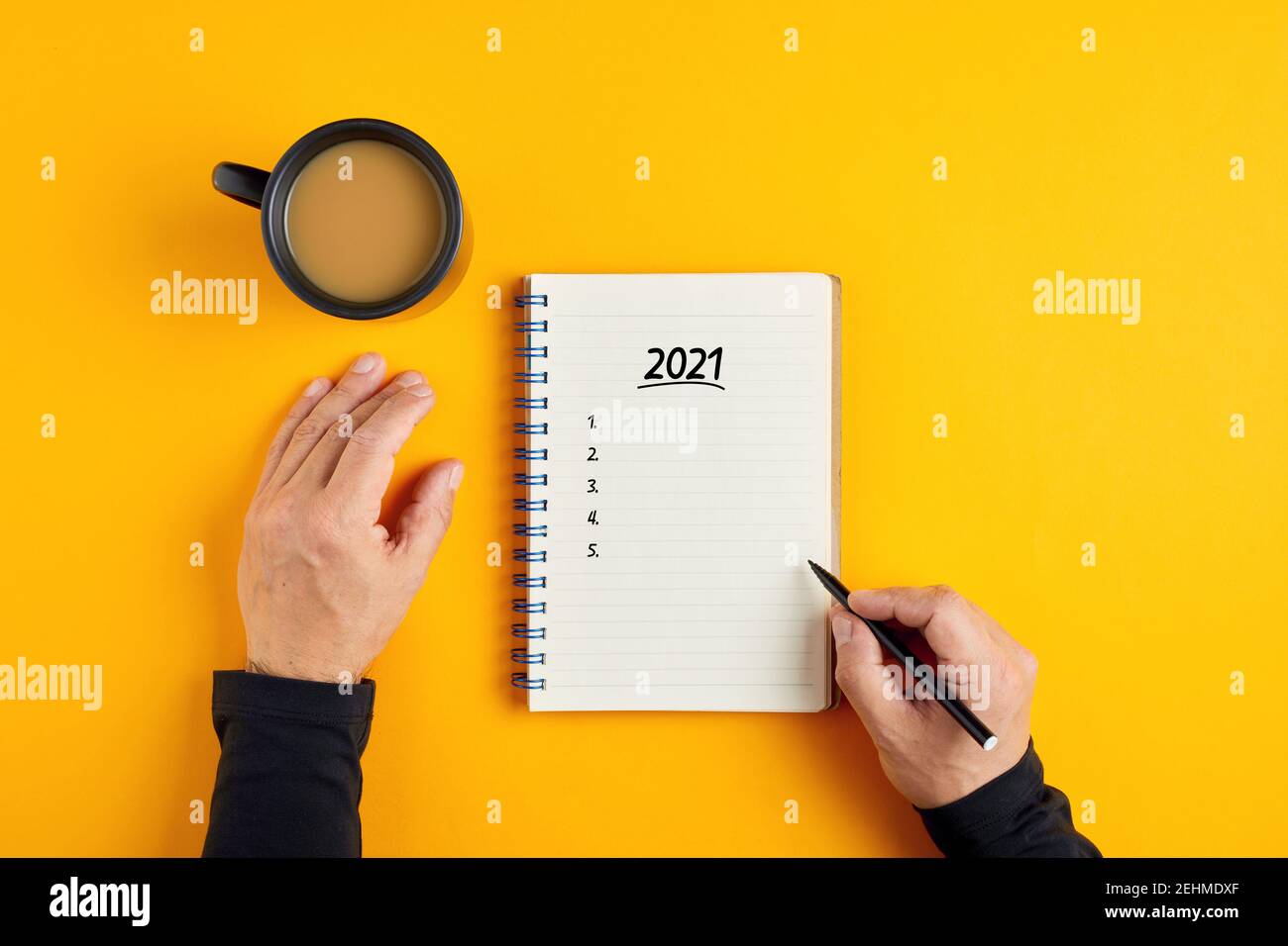 Top view of a man writing down the list of plans for the year 2021 in ...