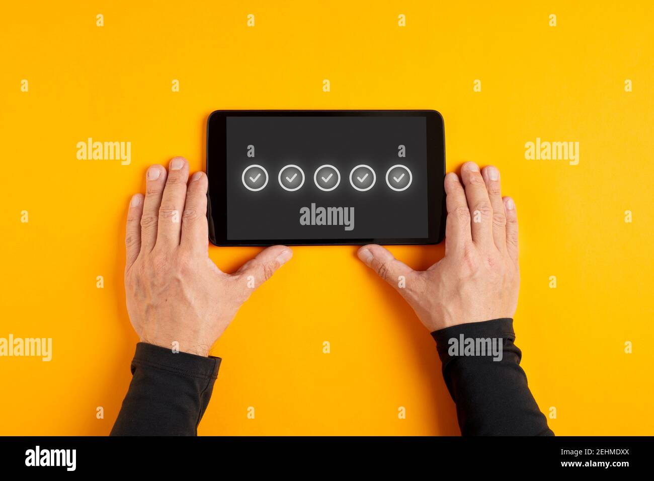Male hand holding a digital tablet displaying check boxes with ticks ...