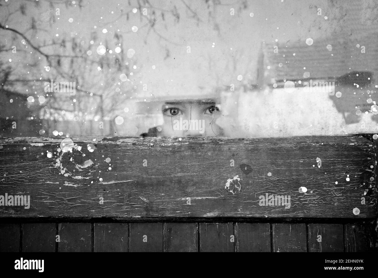 Child fearfully looking through a window Stock Photo - Alamy