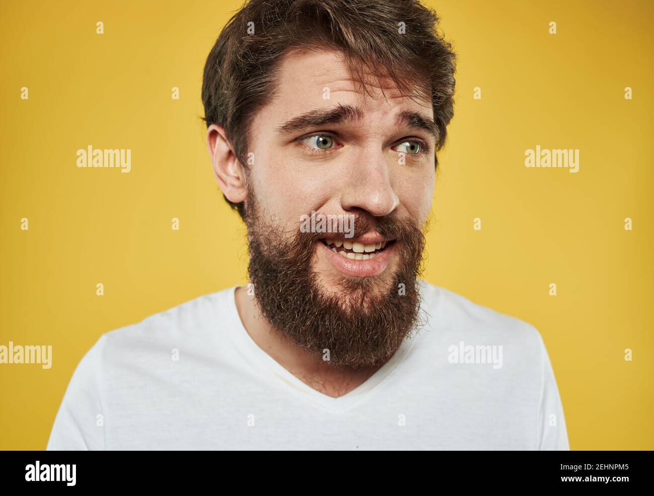 man on a yellow background in a white t-shirt sad face beard model ...