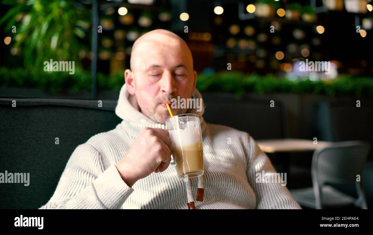 trendy attractive man drinking coffee in cafe. Handsome man drinks ...
