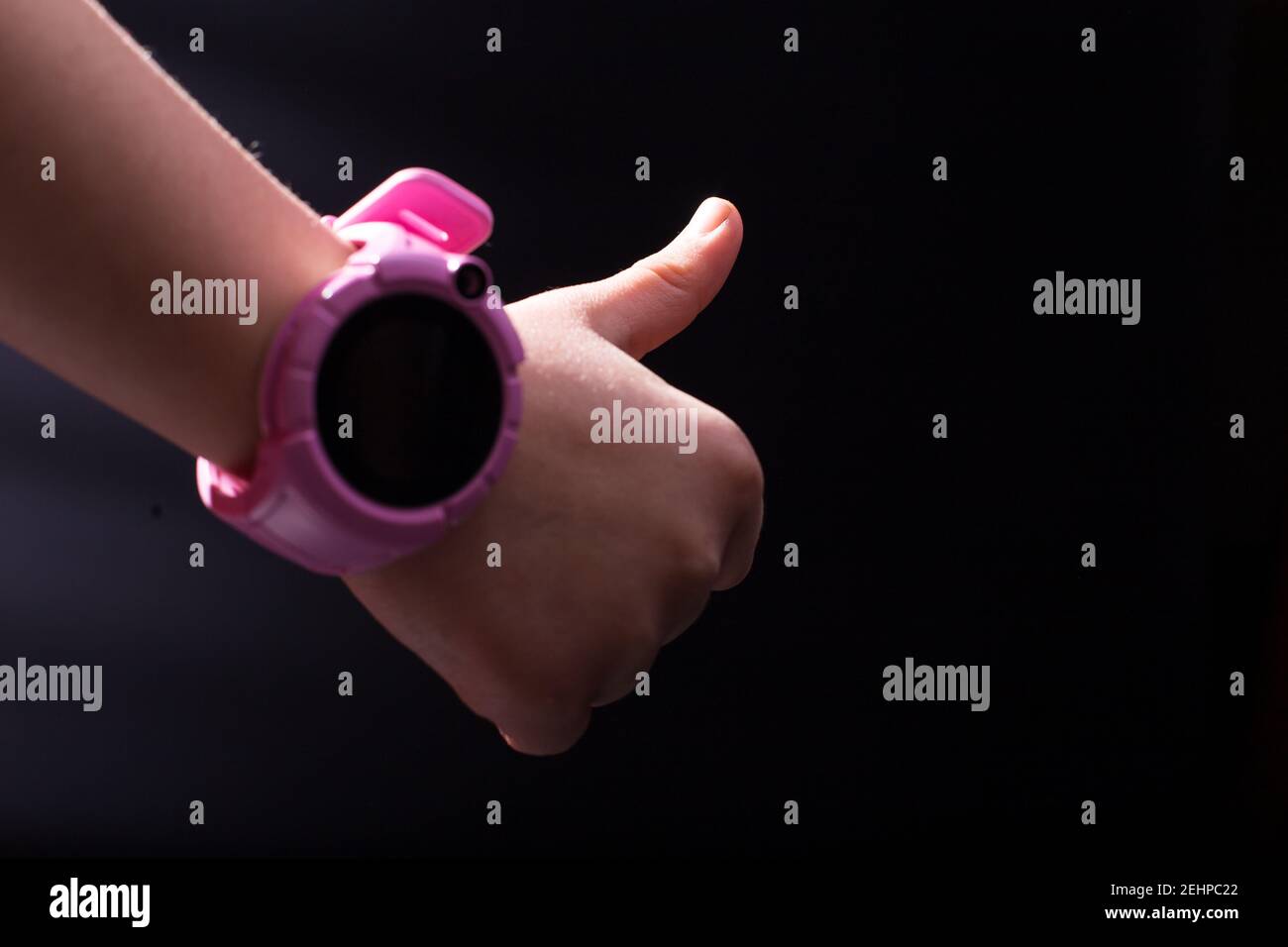 Little child hand with pink smart watch, shows thumb up, isolated on ...