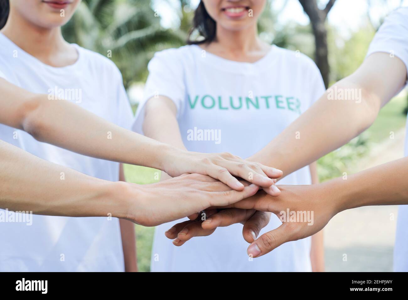 Volunteers standing hands Stock Photo - Alamy